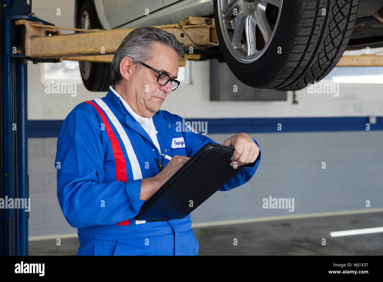 Mechanic writing on clipboard Stock Photo - Alamy