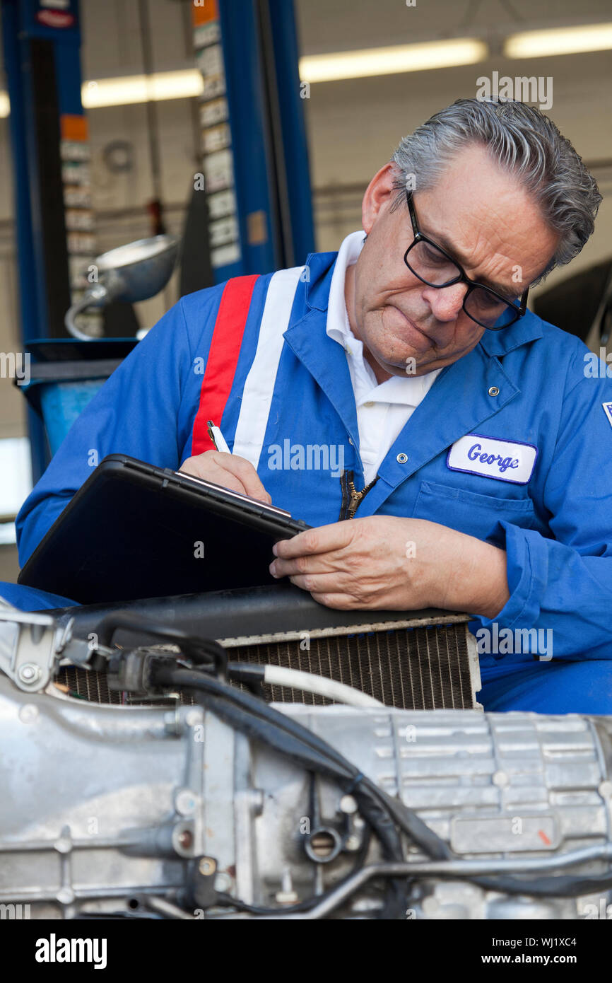 Mechanic writing down something on clipboard Stock Photo - Alamy