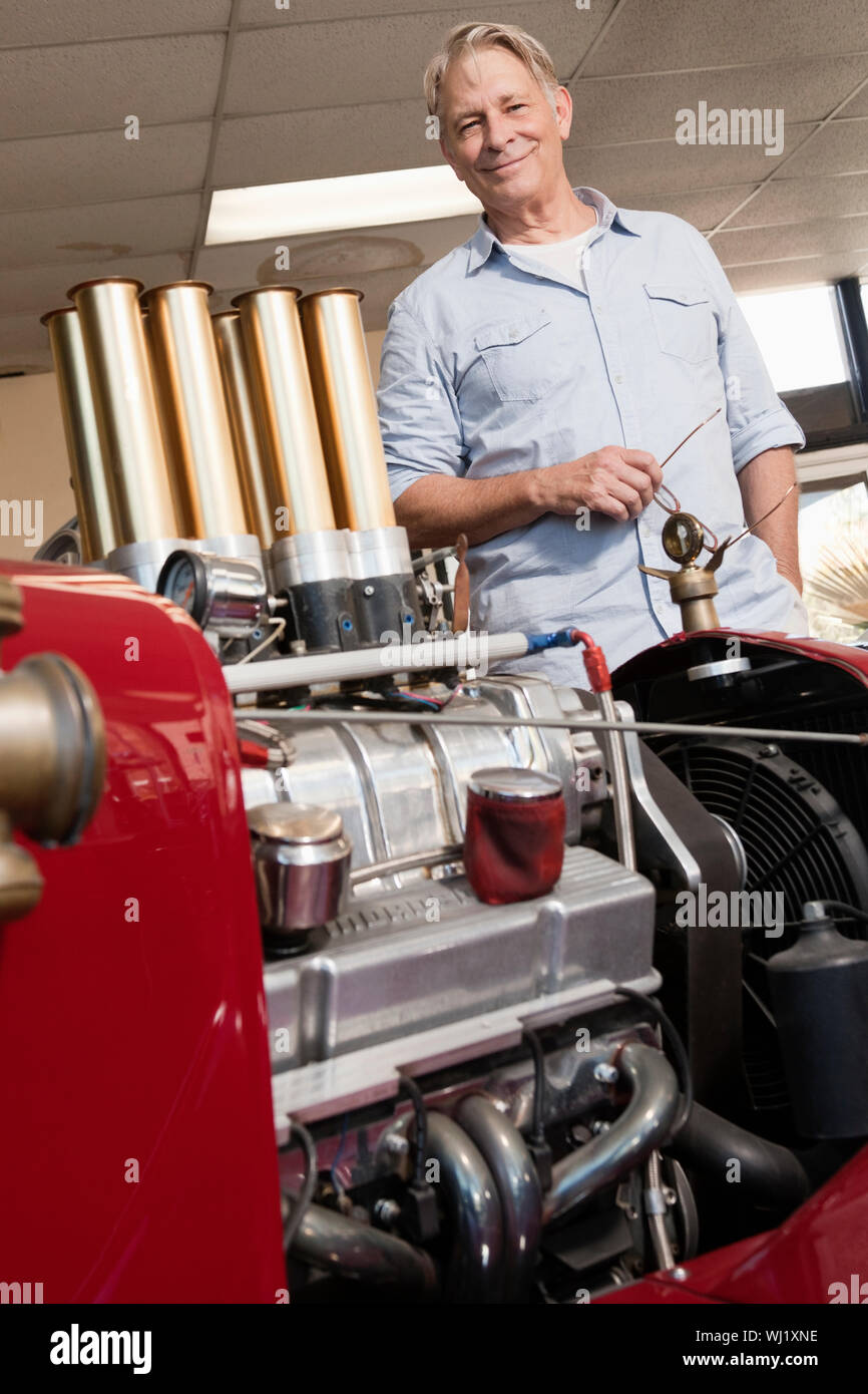Close up of car engine with happy senior man standing behind Stock ...