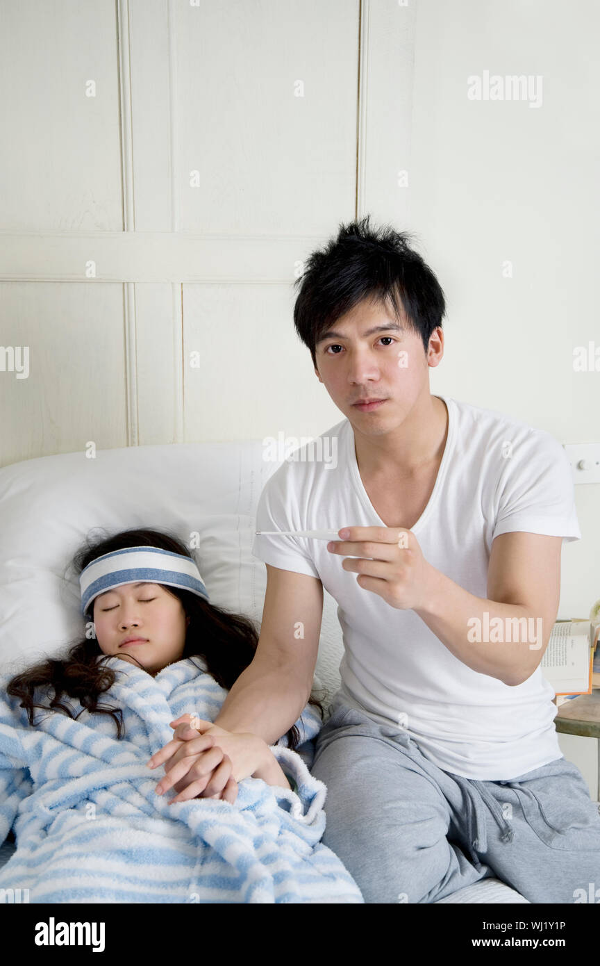 Portrait of young man while woman lying in bed Stock Photo - Alamy