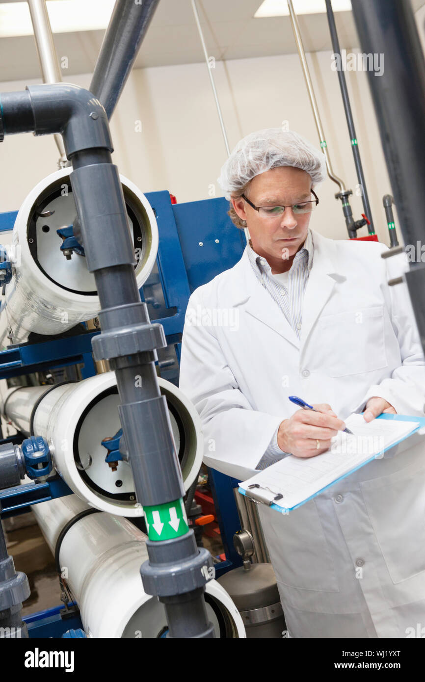 Man writing in clipboard while standing in bottling factory Stock Photo ...