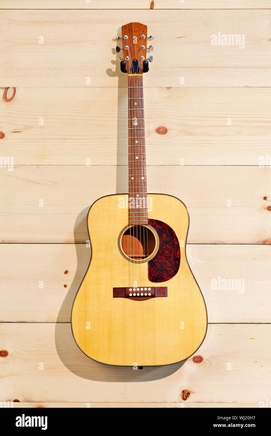 Steel-string acoustic guitar on wood grain wall Stock Photo - Alamy