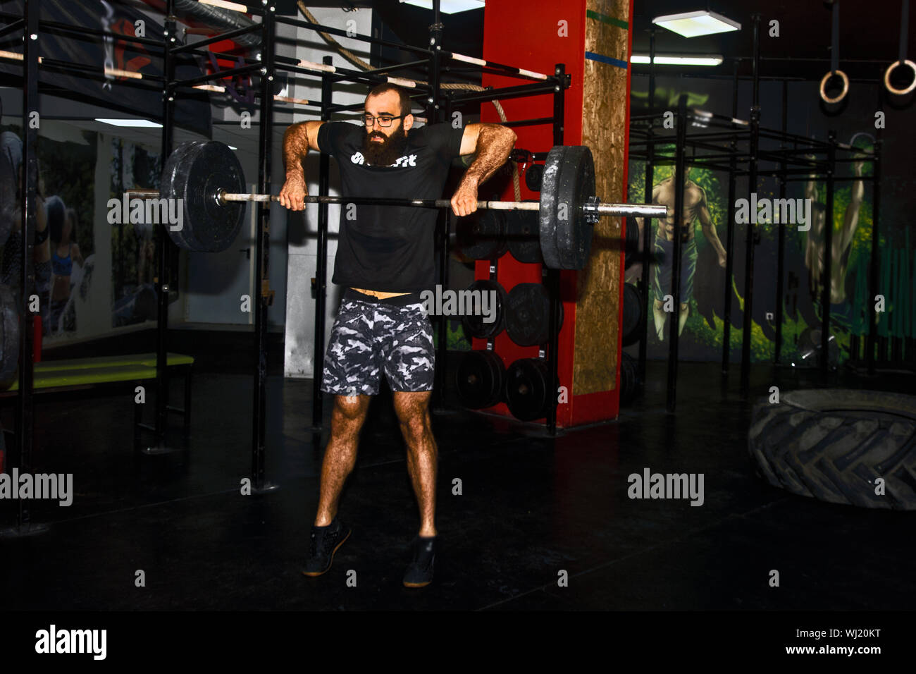 A strong and young man exercises weight lifting to strengthen the body ...