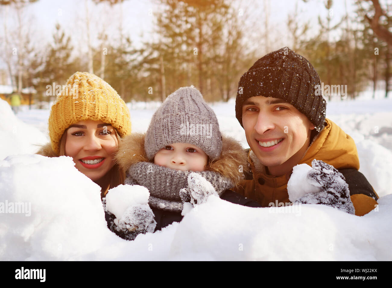 Happy beautiful family is playing snow fight. Mom, son and dad are ...