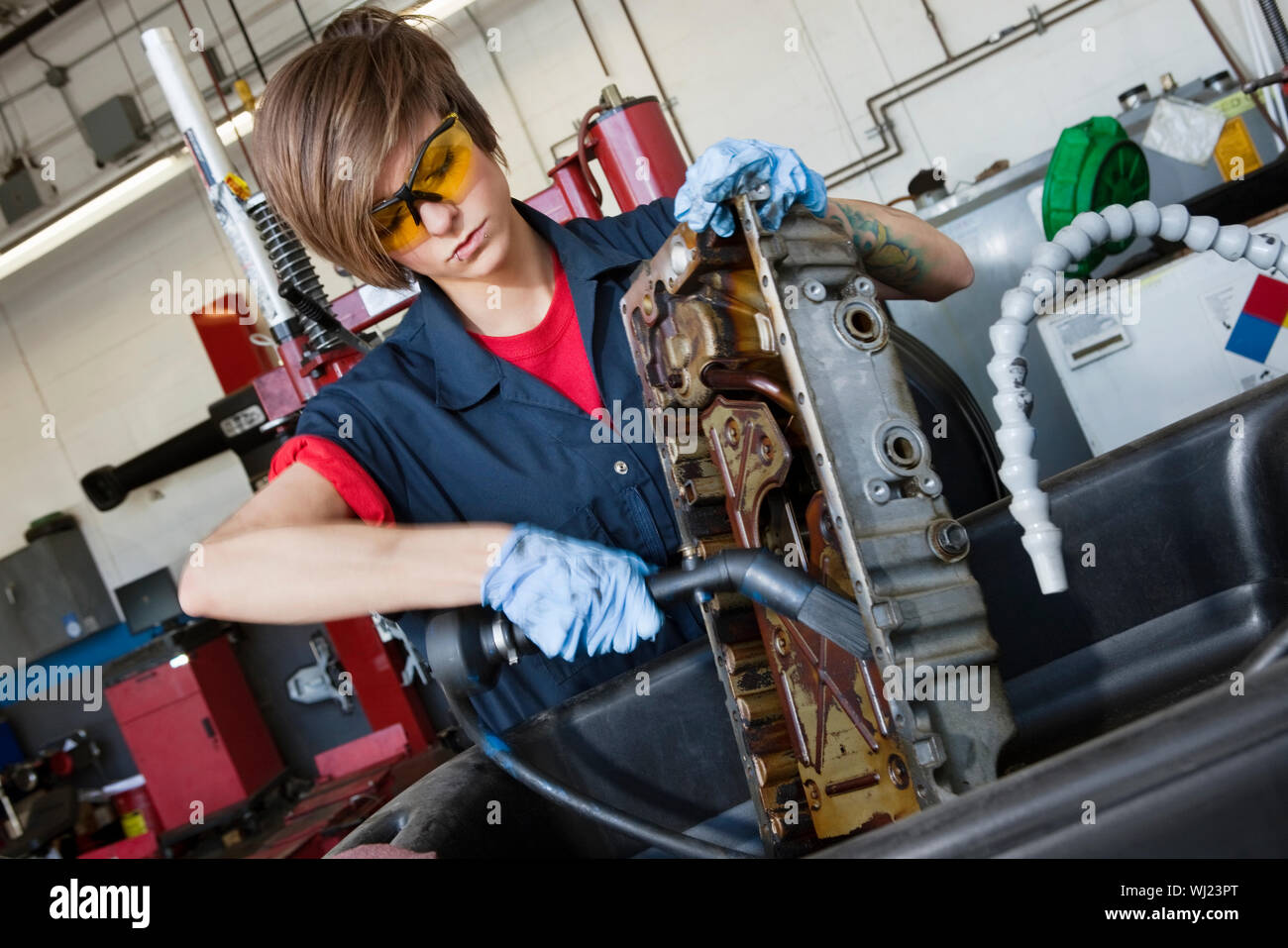 Young female mechanic working with welding torch on vehicle machinery ...