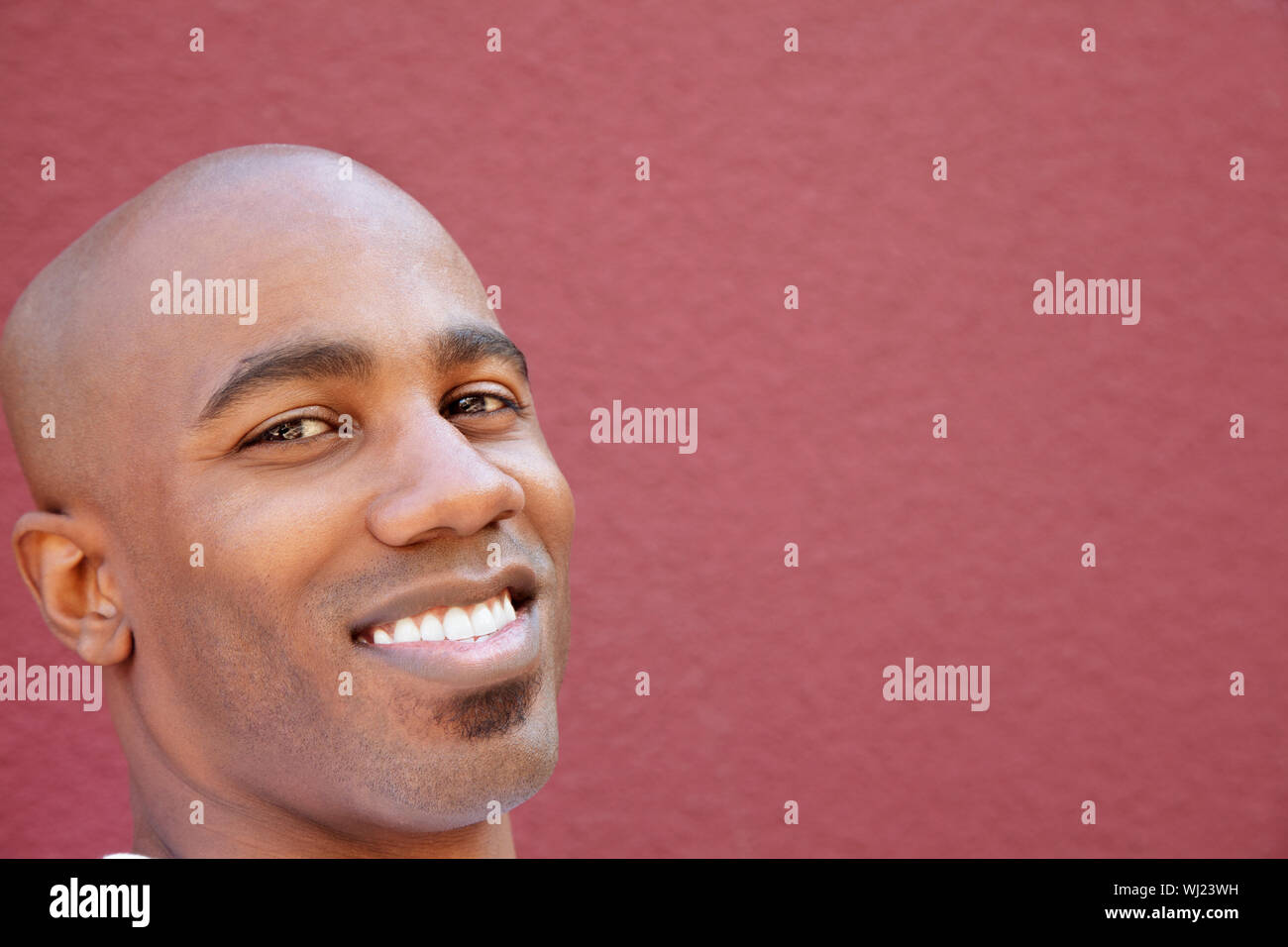Close-up portrait of bald African American man over colored background ...