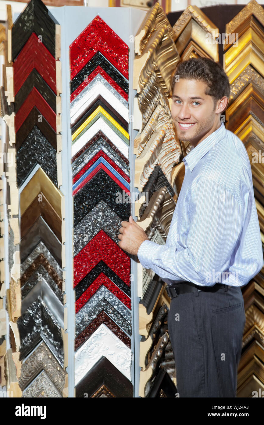 Portrait of a happy young man browsing at a frame store Stock Photo - Alamy