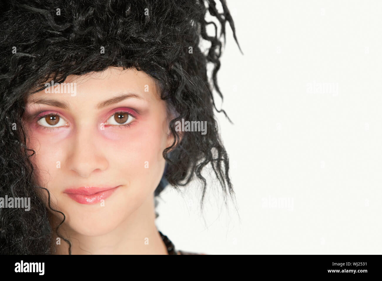 Close-up portrait of beautiful young woman with teased hair over gray ...