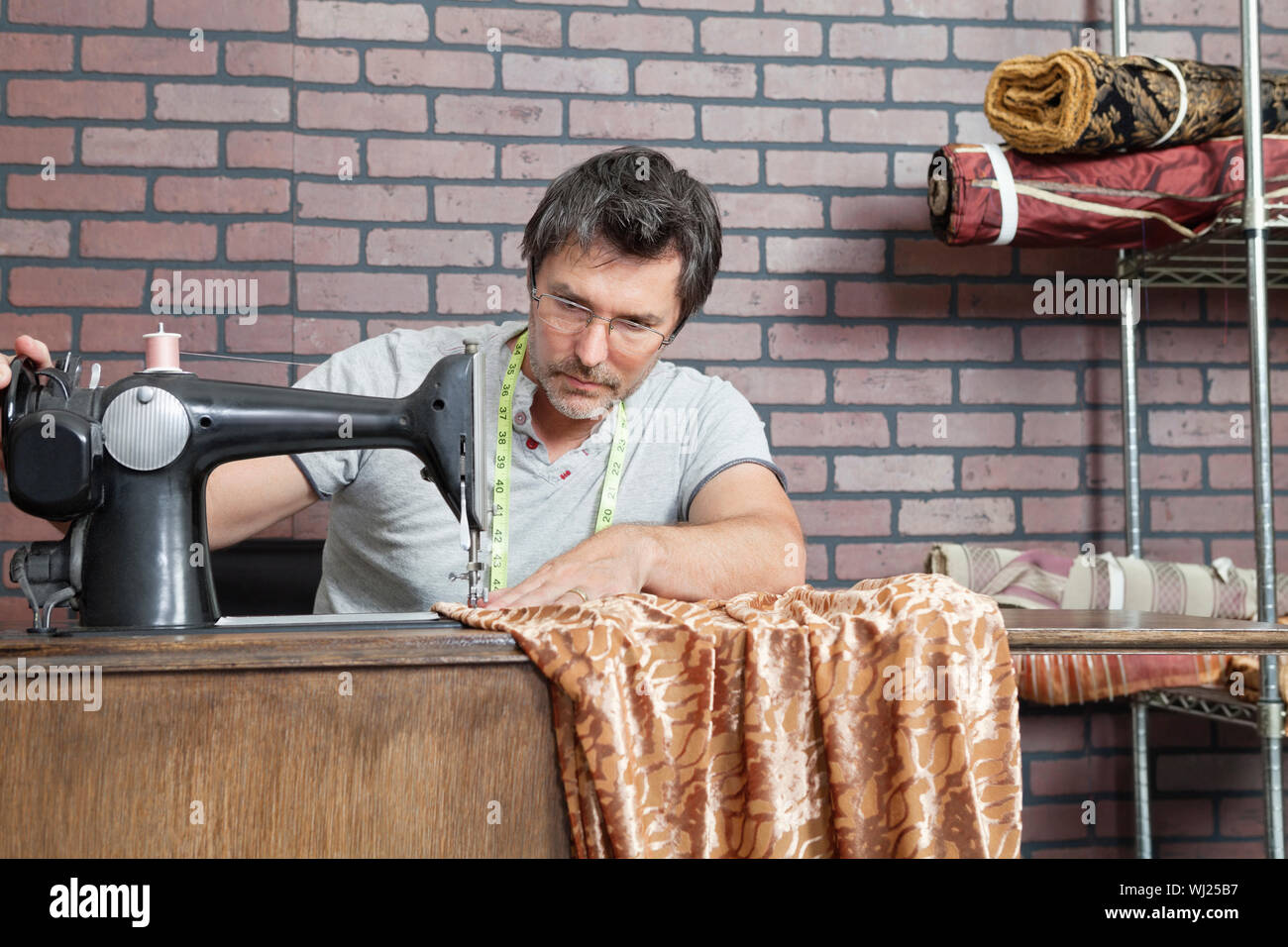 Mature male dressmaker stitching cloth on sewing machine Stock Photo ...