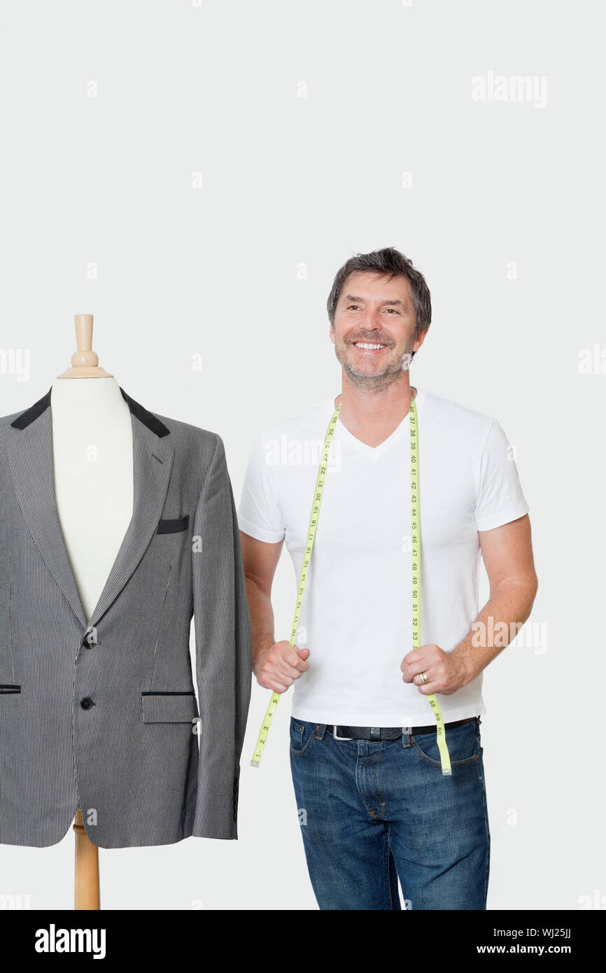 Mature male dressmaker standing next to tailor's dummy over gray ...