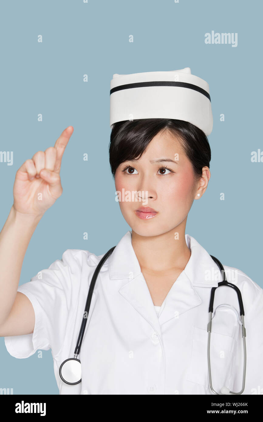 Young nurse using transparent screen over light blue background Stock ...