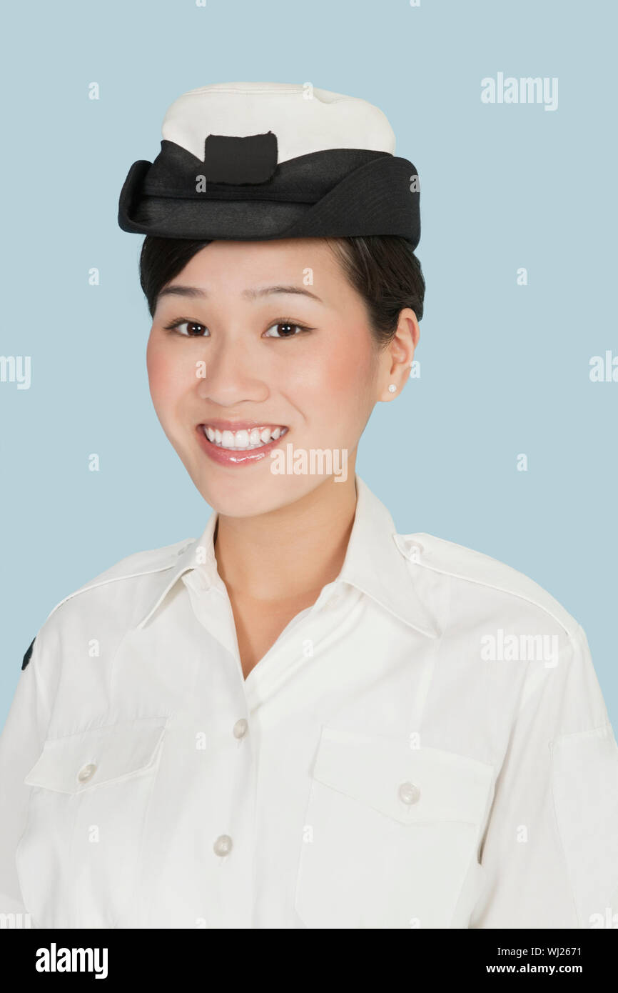 Portrait of beautiful young Navy officer smiling over light blue ...