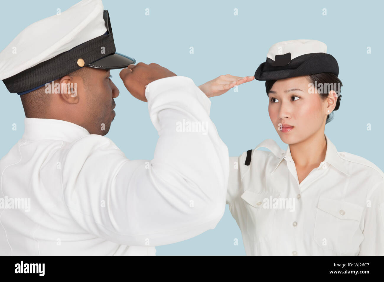 Multi-ethnic Navy officers saluting each other over light blue ...