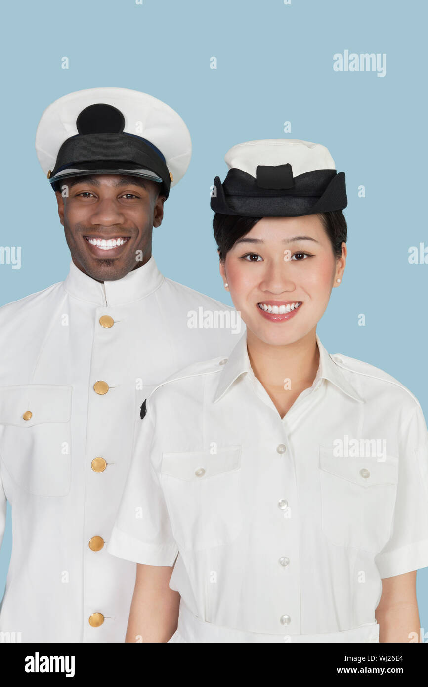 Portrait of two happy young Navy officers standing against light blue ...