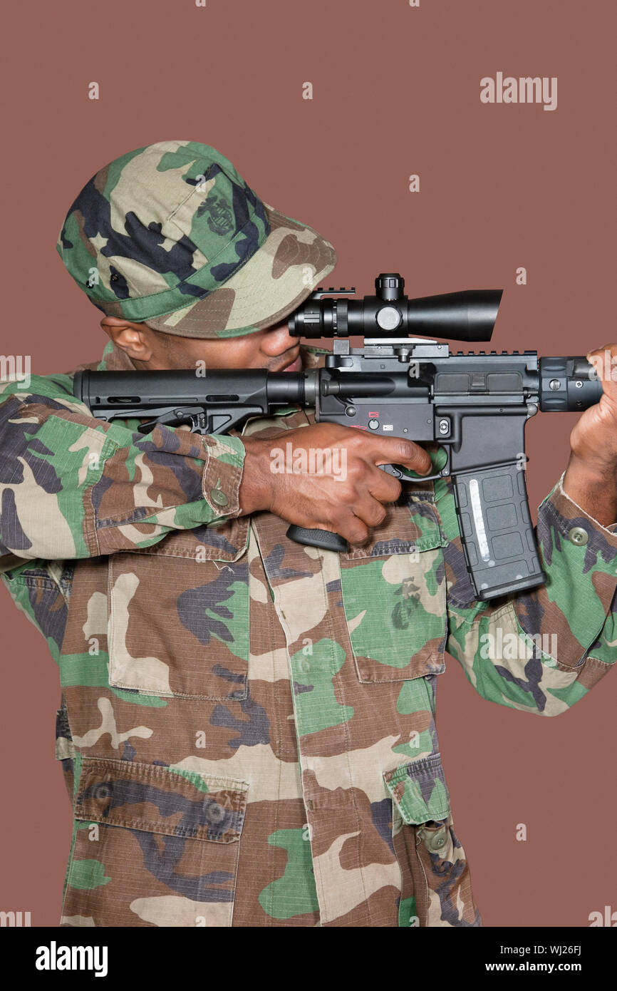Male US Marine Corps soldier aiming M4 assault rifle over brown ...