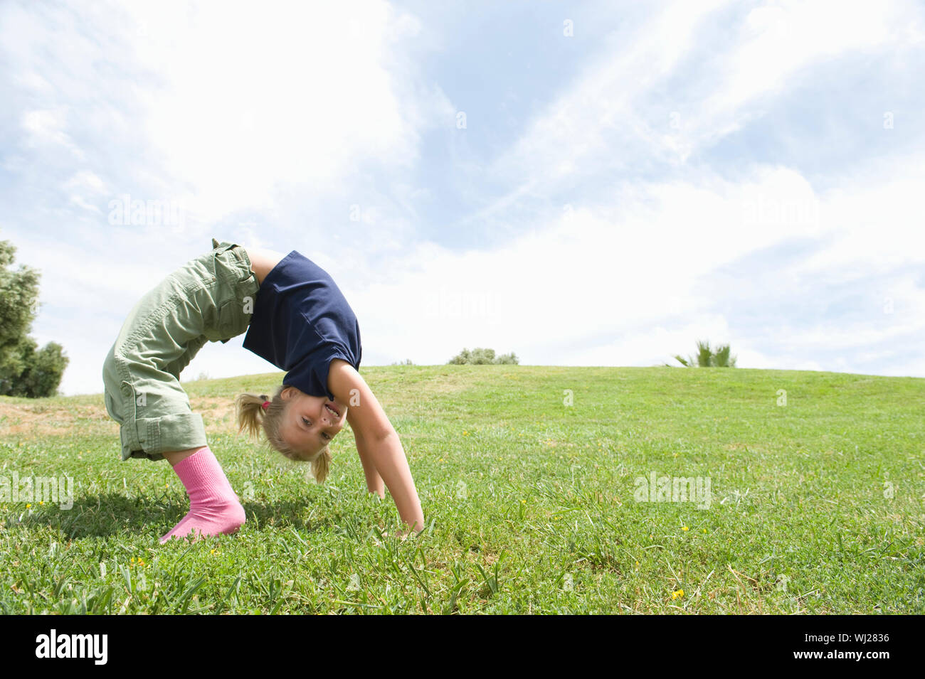 Little girl doing bridge in park against cloudy sky Stock Photo - Alamy