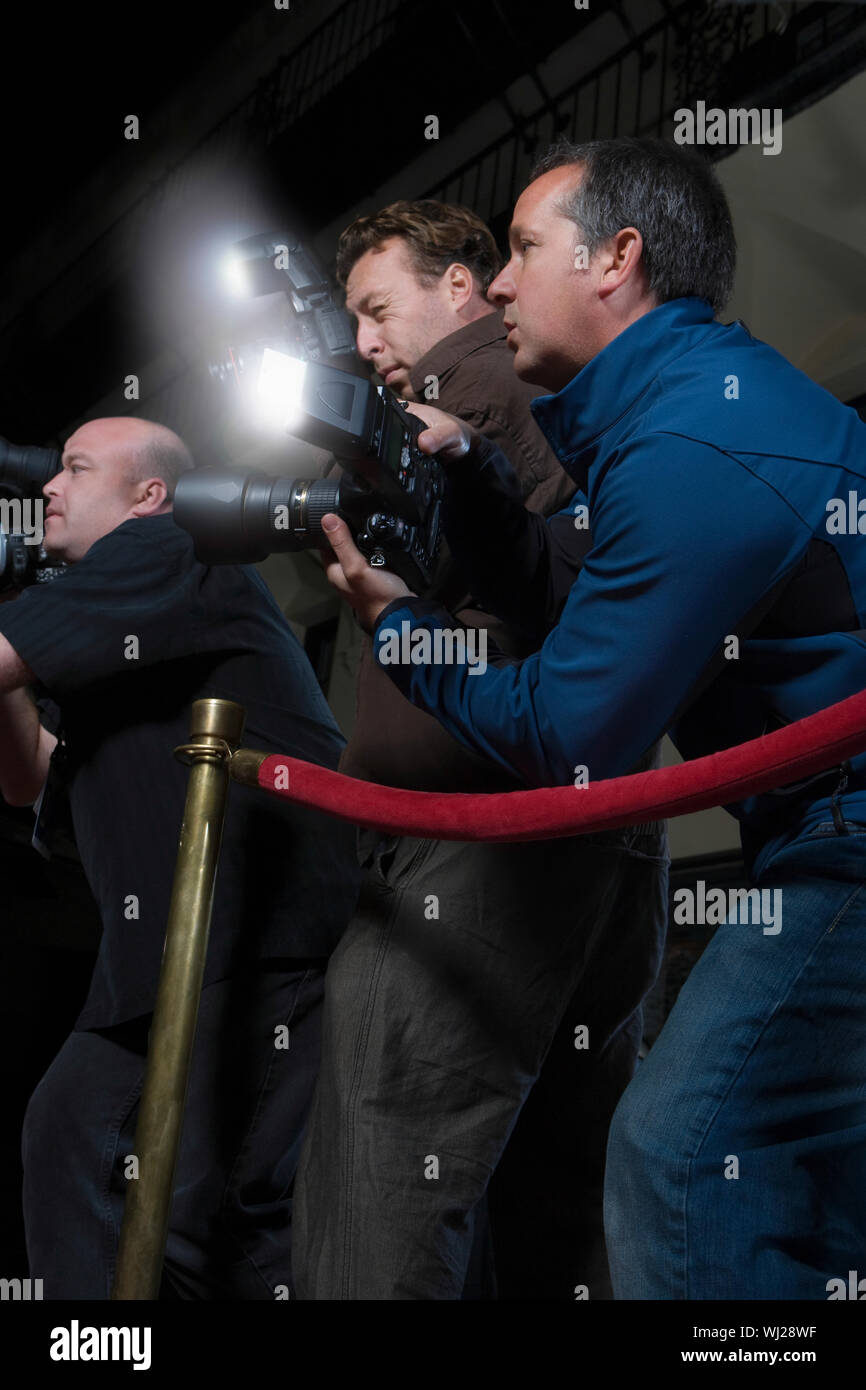 Side view of photographers across rope barrier at media event Stock ...