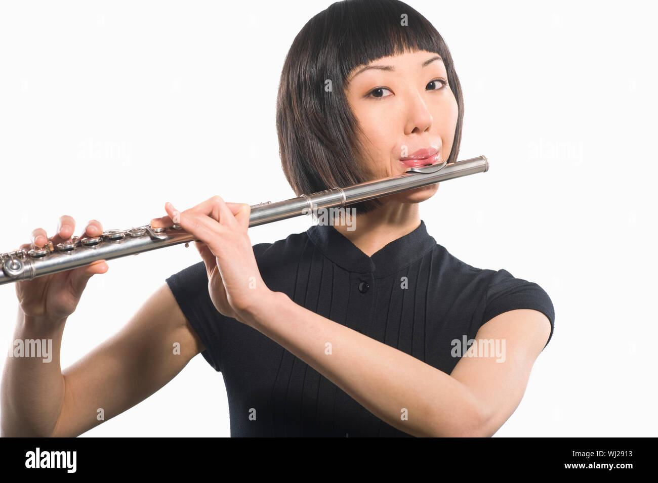 Portrait of a pretty female playing flute isolated over white ...