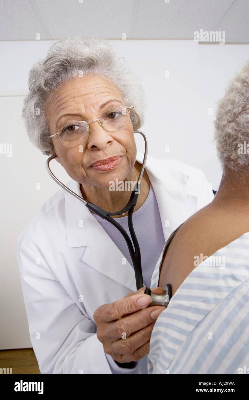 Portrait of senior female doctor checking patient's back using ...
