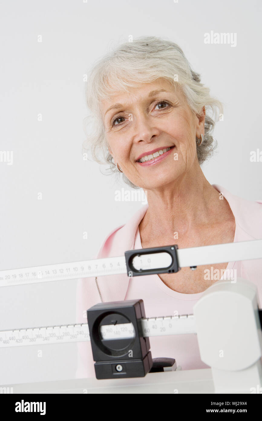 Closeup of beautiful senior woman patient with weight scale in clinic ...