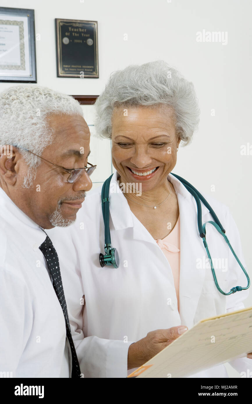 Two African American happy senior doctors looking at a document in ...