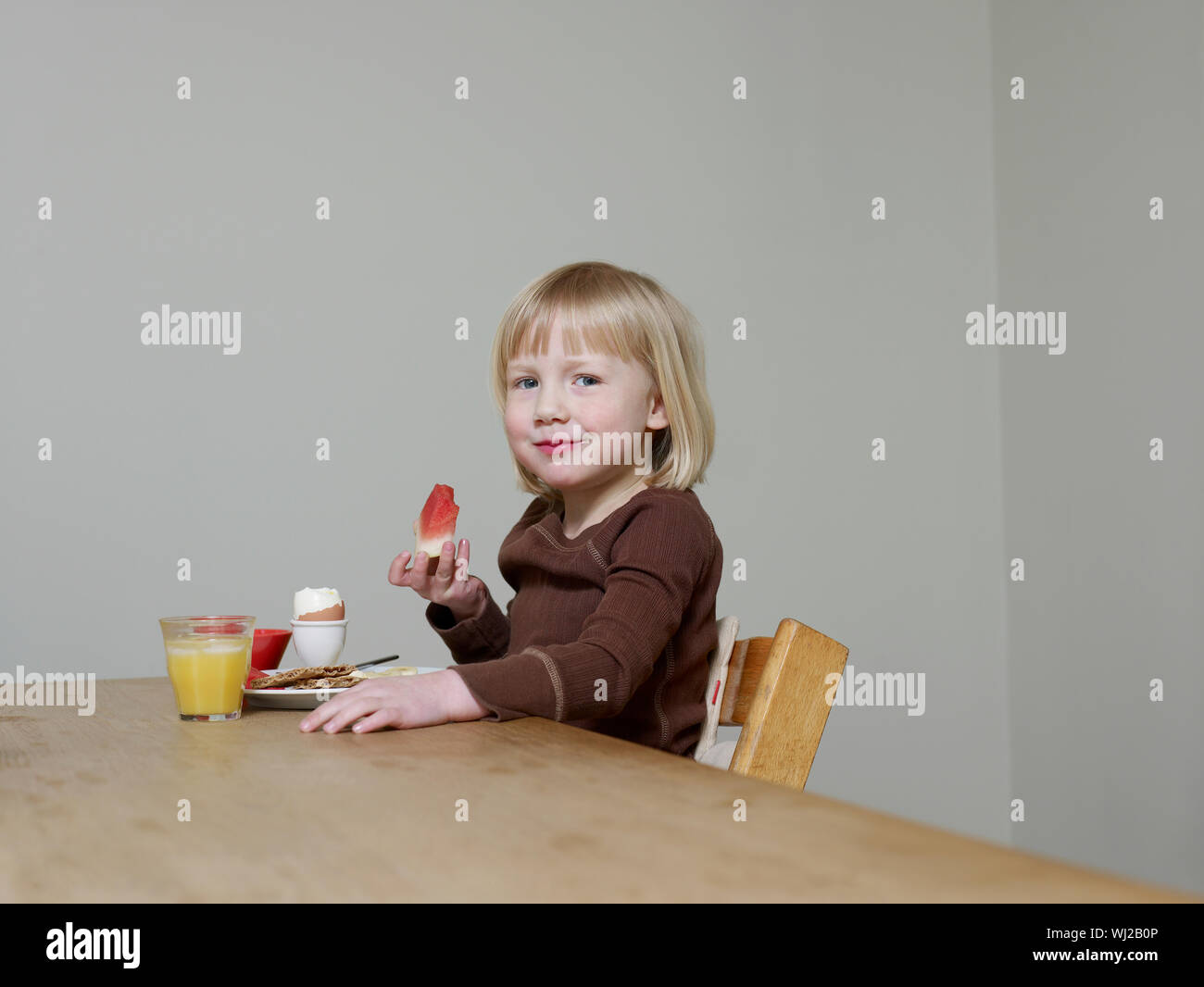 Side view portrait of a little blond girl eating breakfast at dining ...
