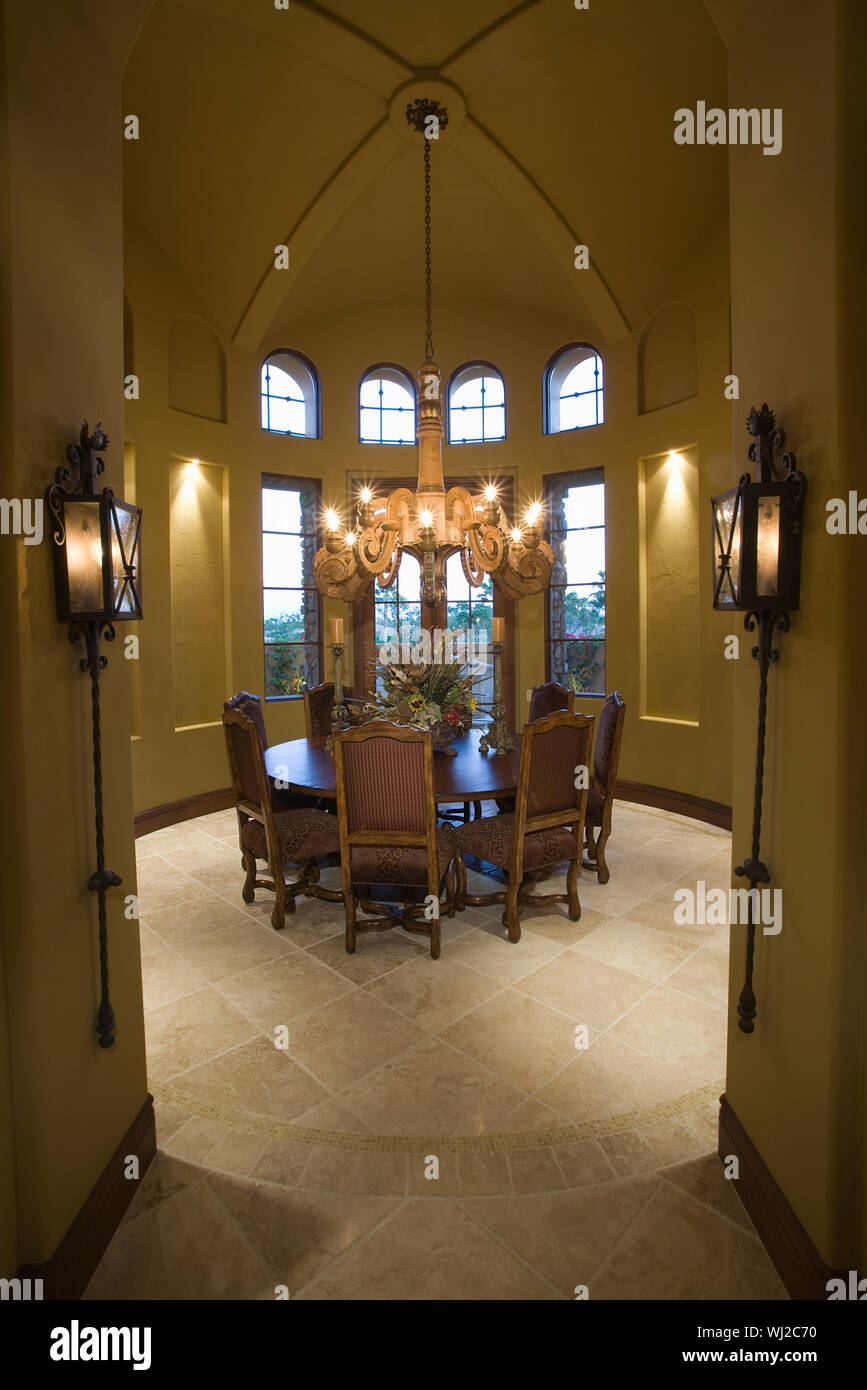 Lit chandelier hanging over table in hallway at modern home Stock Photo ...