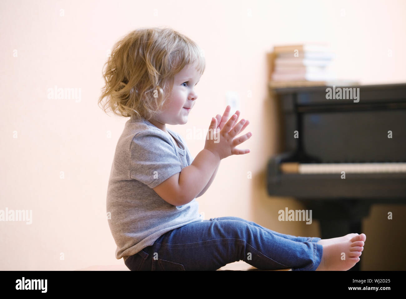 Full length side view of happy little boy clapping at home Stock Photo ...