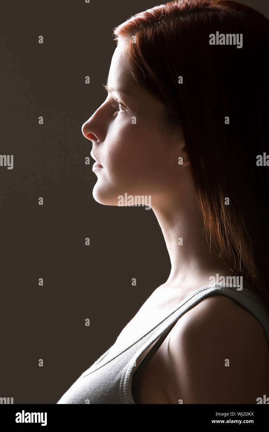 Closeup side view of serious young woman over black background Stock ...