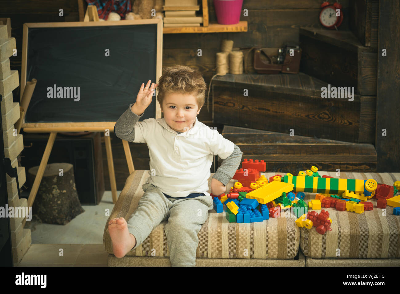 Childhood concept. Boy plays with construction bricks in playroom near ...