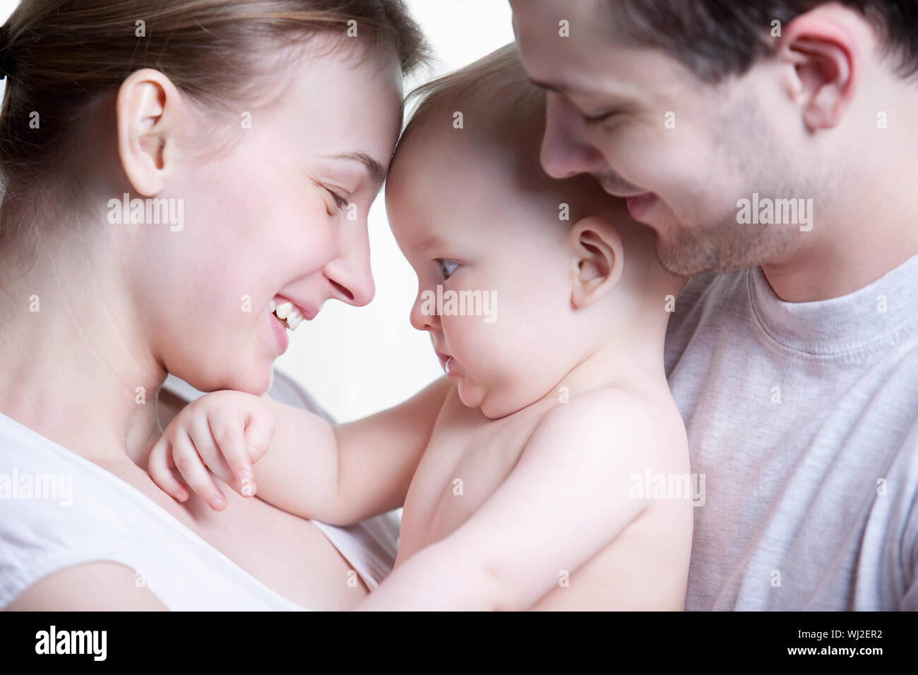 Closeup side view of happy young family with their little son on white ...