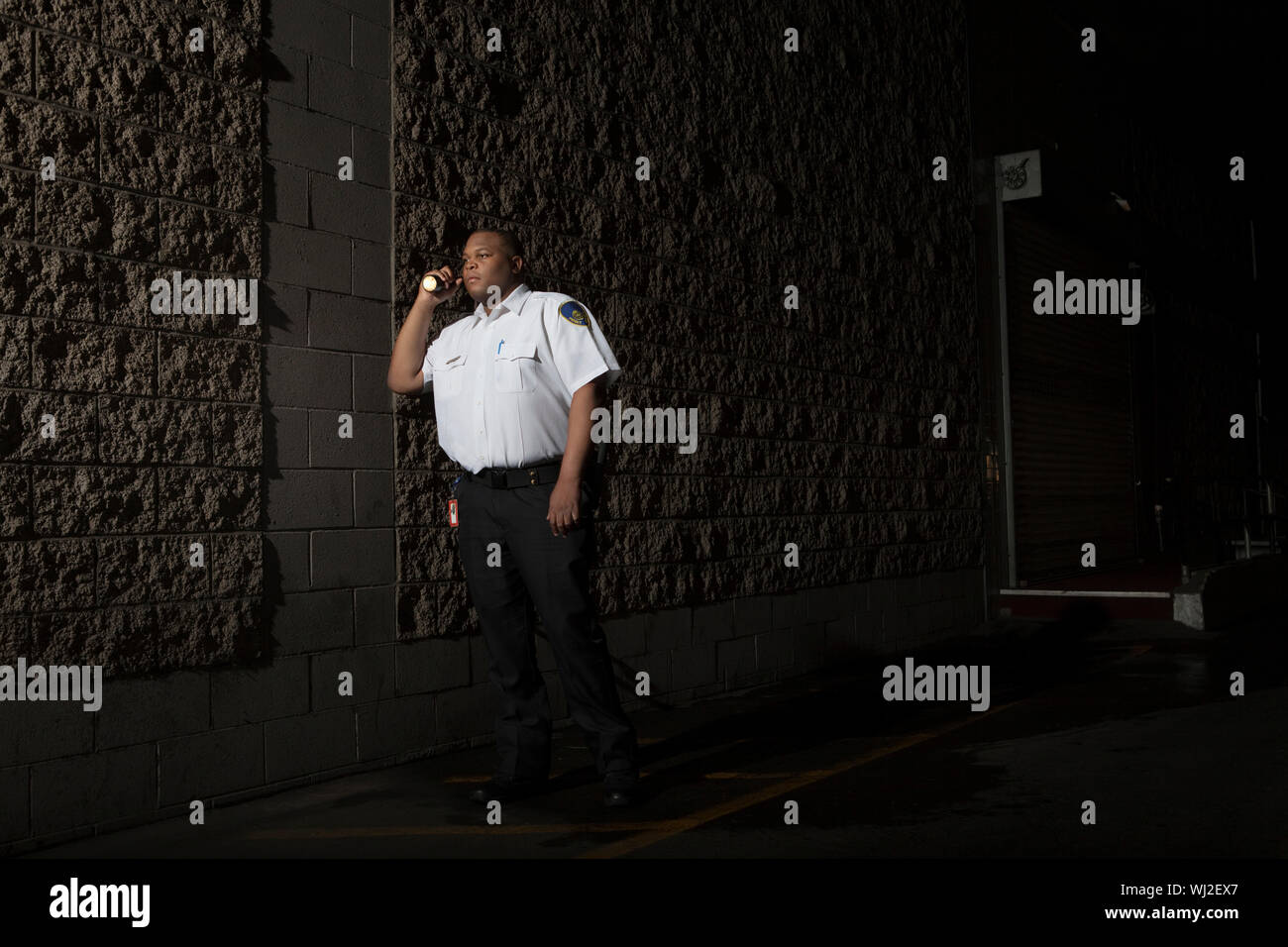 Young security guard with torch patrols on duty Stock Photo - Alamy