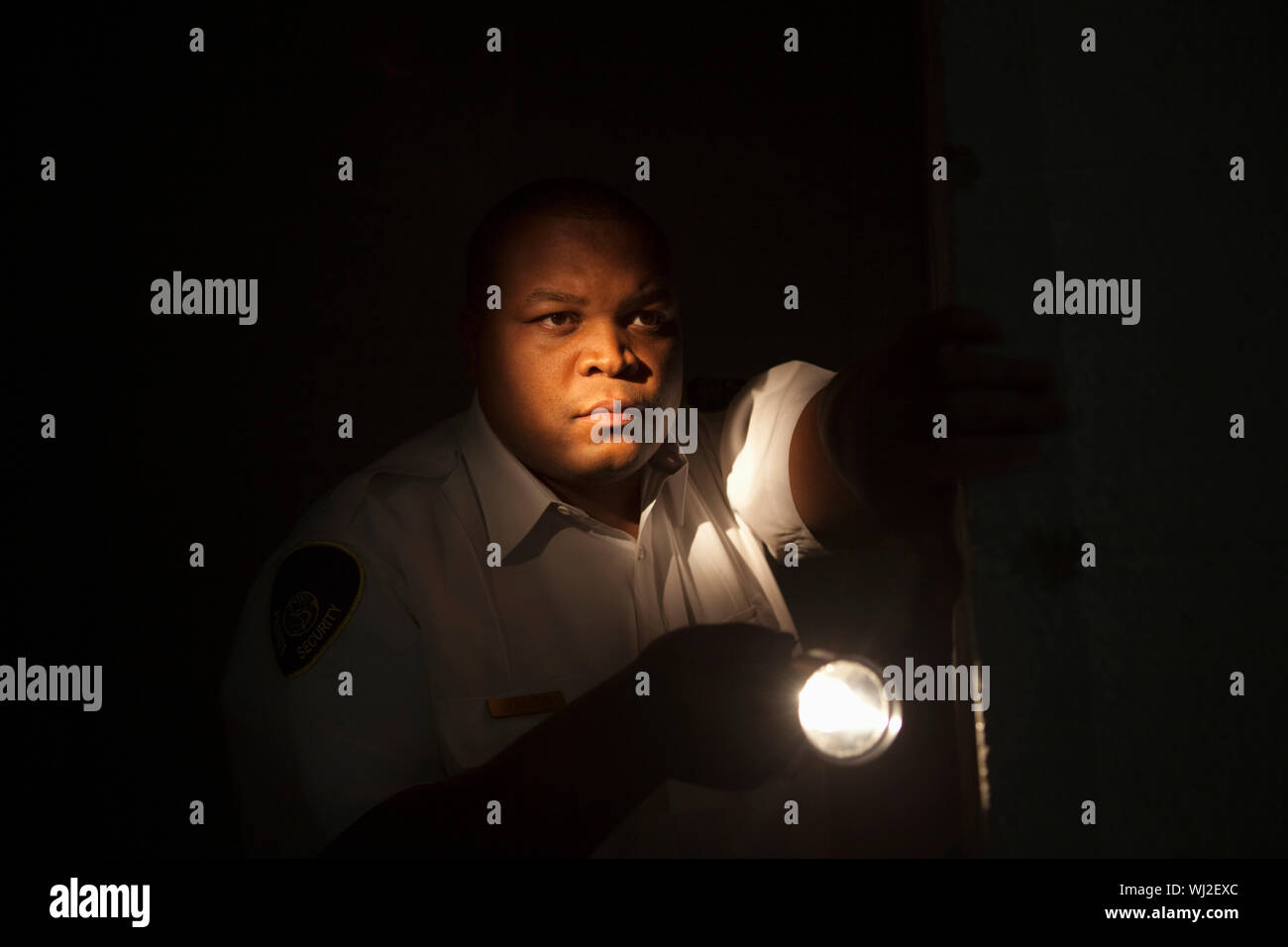 Closeup of young security guard with torch light on duty Stock Photo ...
