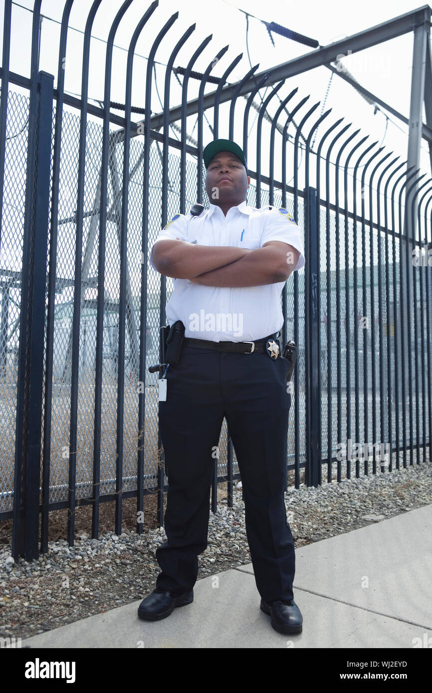 Full length of a confident security guard standing with arms crossed in ...