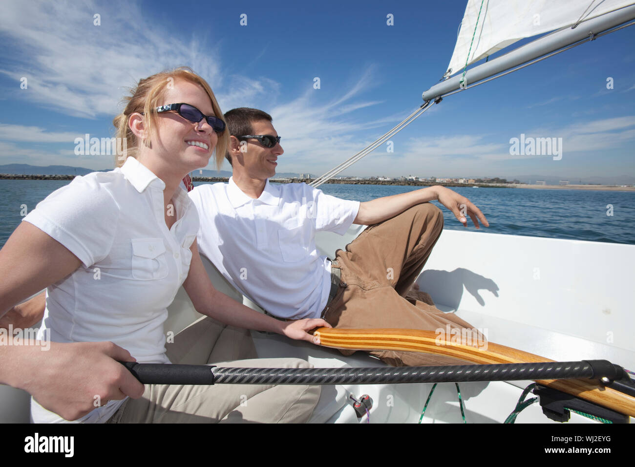Happy multiethnic couple sailing together on sailboat Stock Photo - Alamy