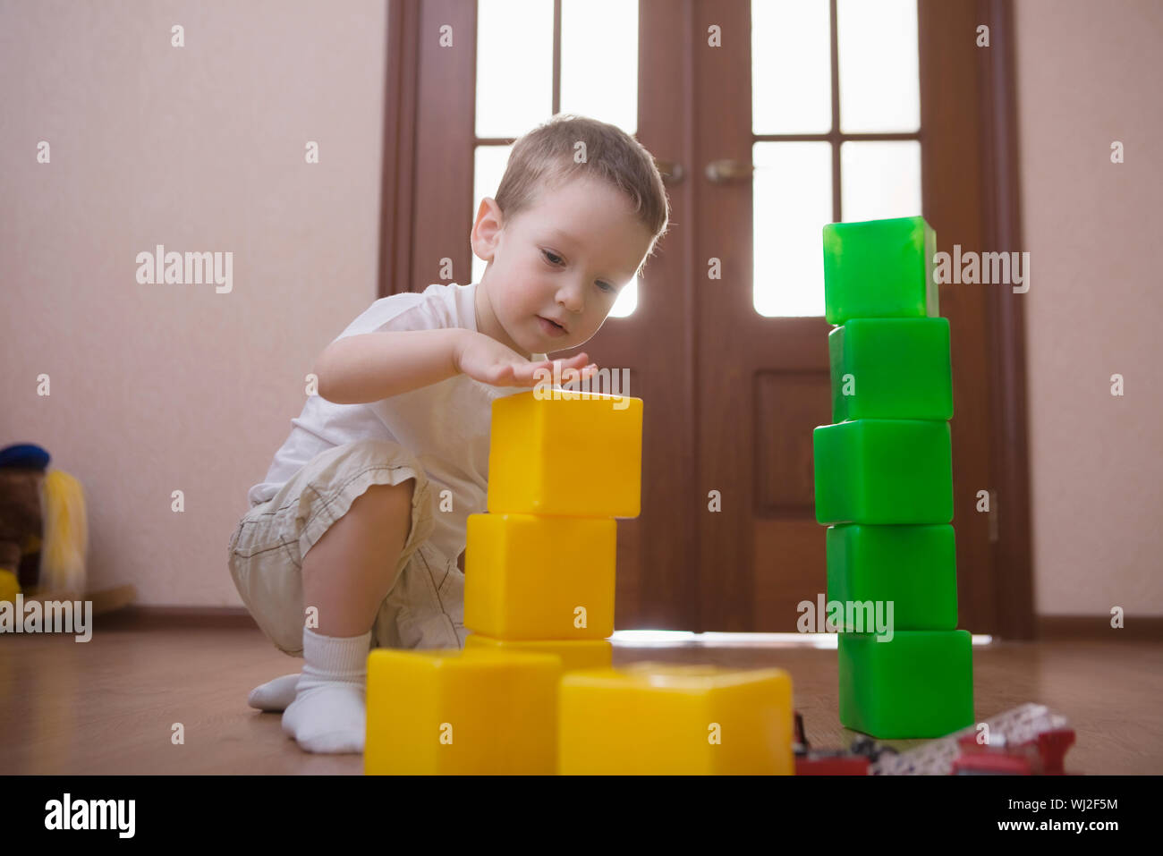 Young boy building towers from colorful cubes at home Stock Photo - Alamy