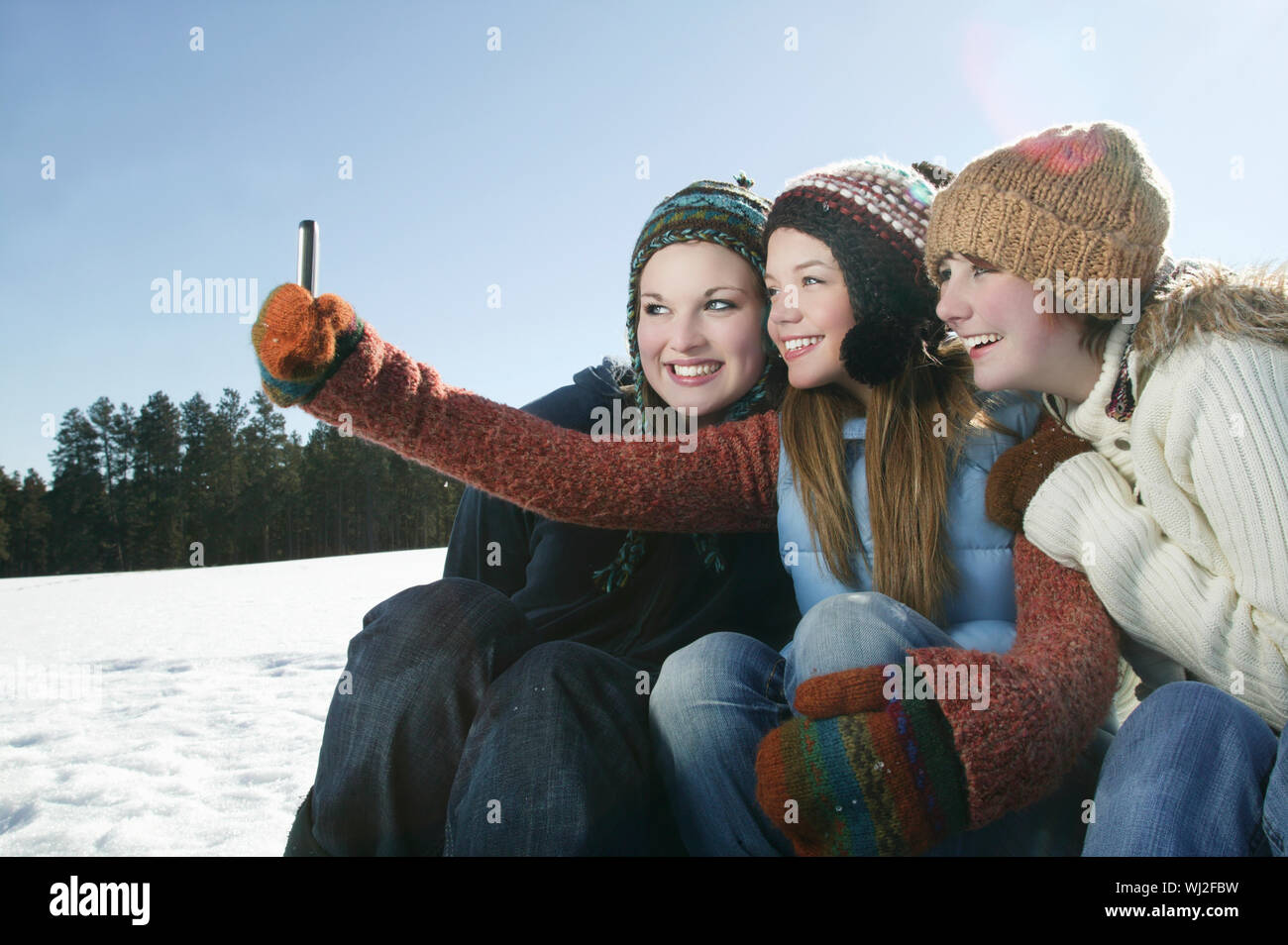 Three female friends taking self portrait in snow Stock Photo - Alamy