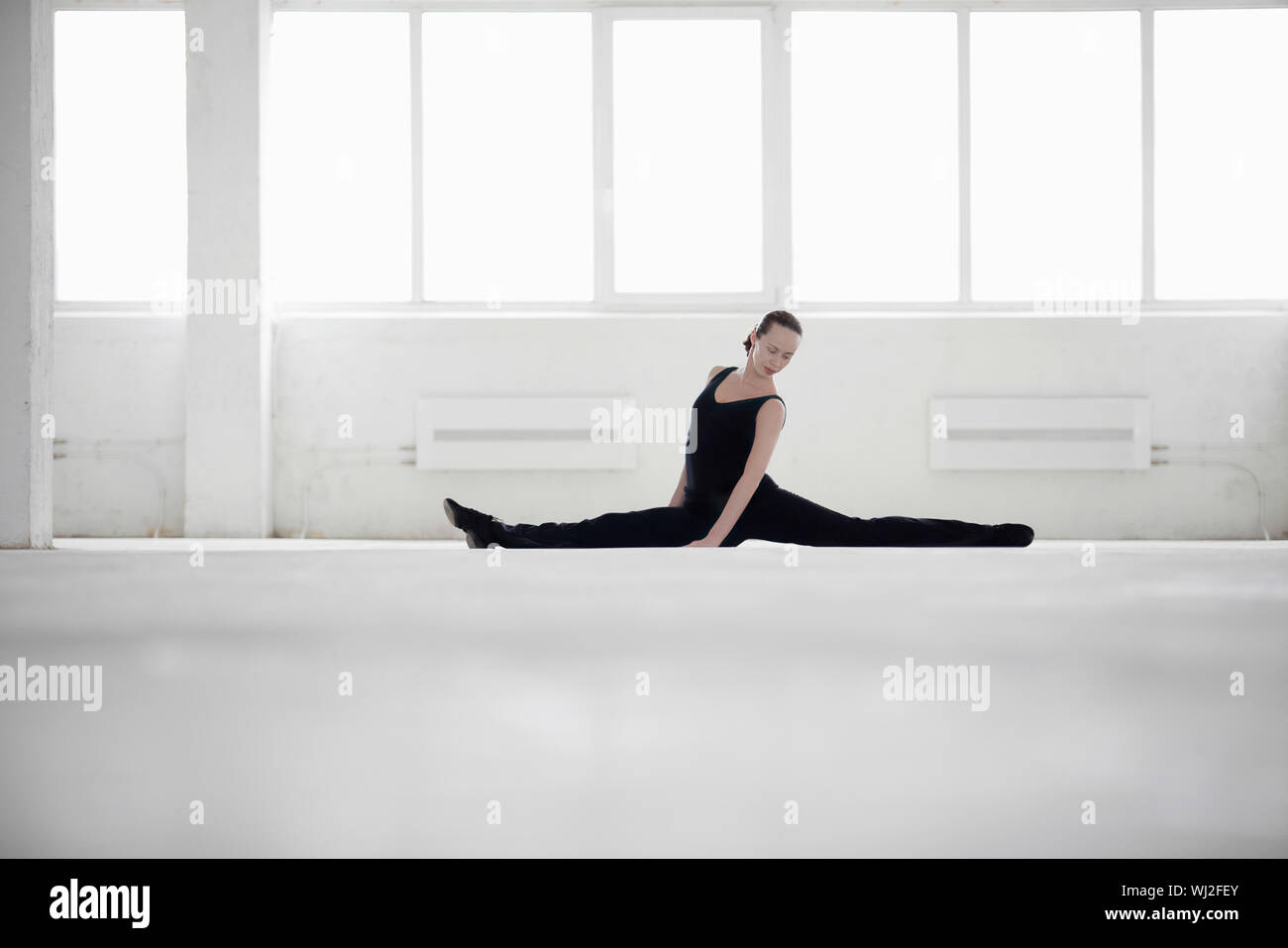 Full length of female dancer doing splits in empty warehouse Stock ...