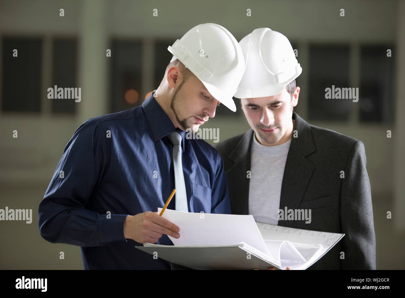 Young male architects going through file folder in warehouse Stock ...