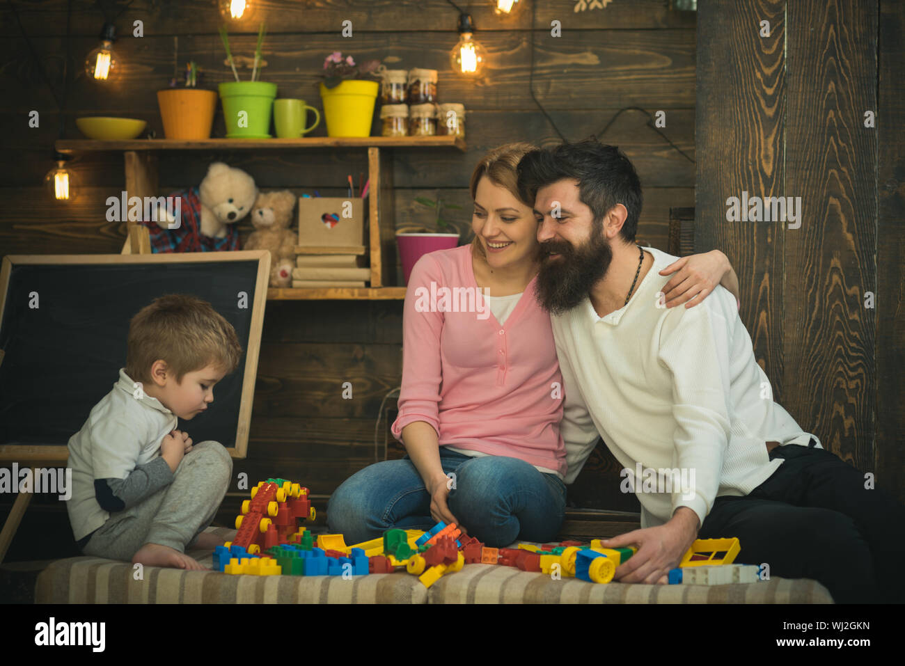 Happy parents hug each other while looking at son. Family playing with ...