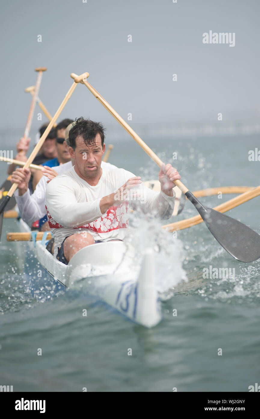 Confident male rower with team paddling outrigger canoe in race Stock ...