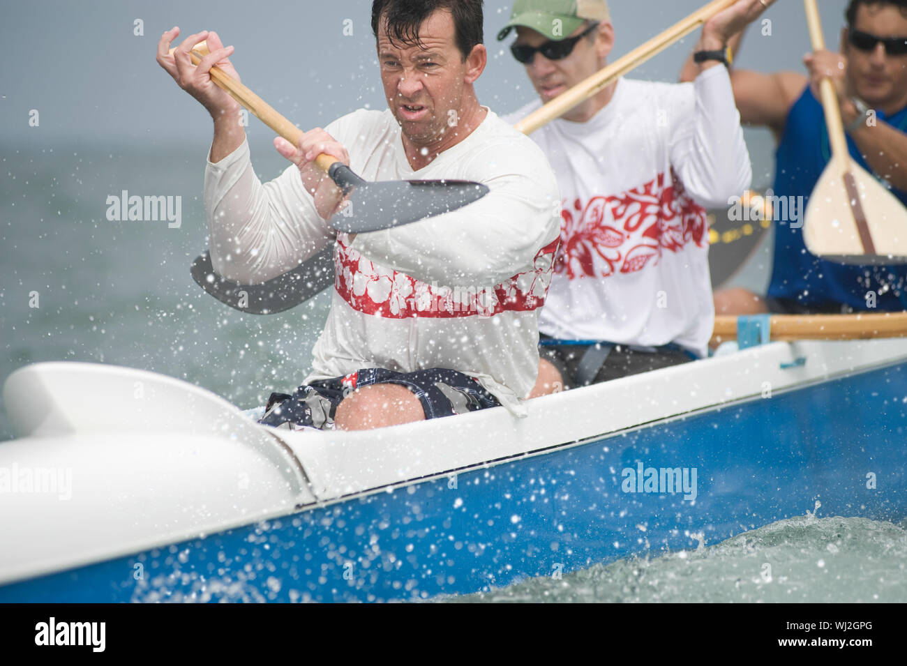 Confident male rower with team paddling outrigger canoe in race Stock ...