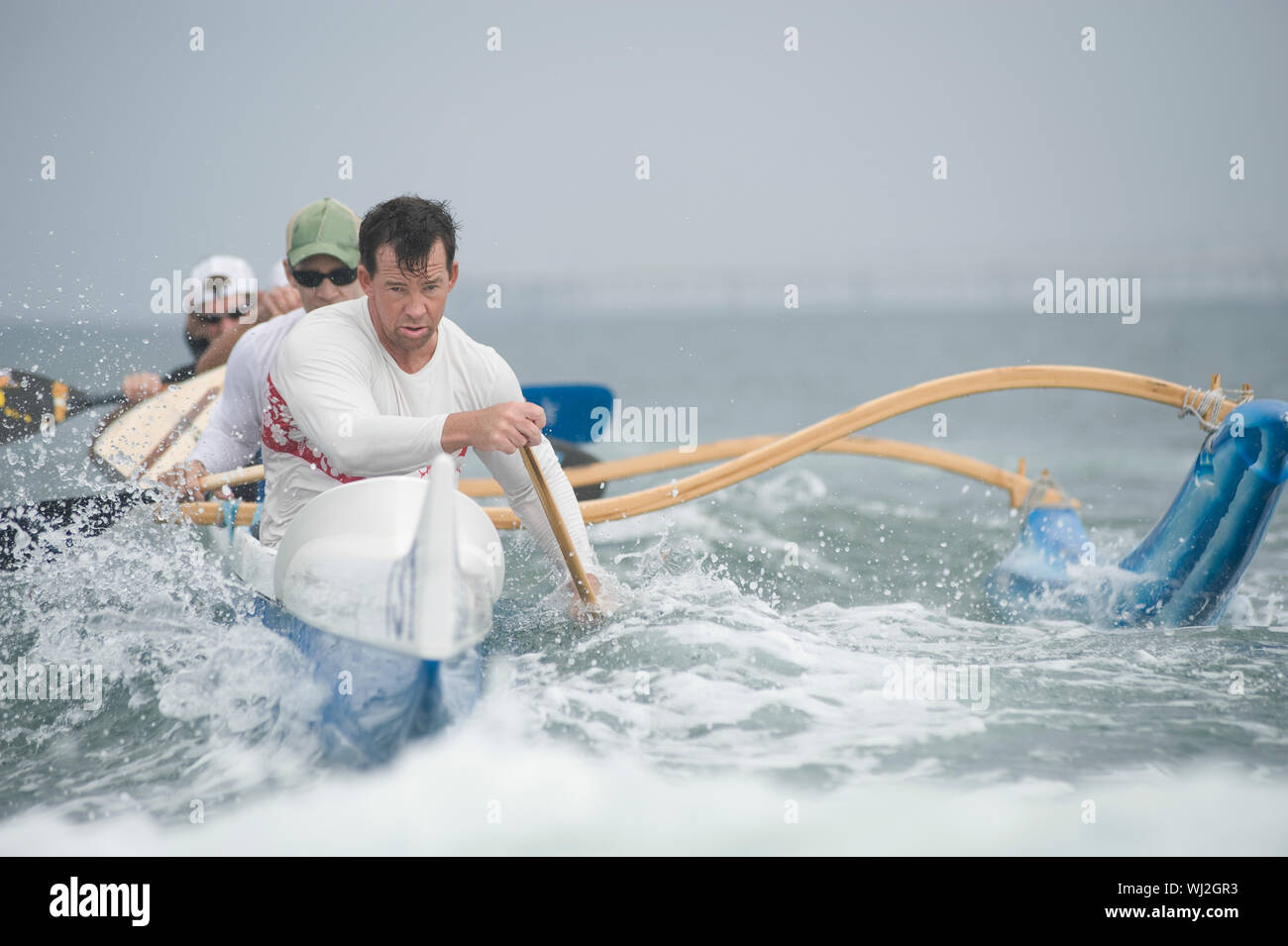 Confident male rower with team paddling outrigger canoe in race Stock ...