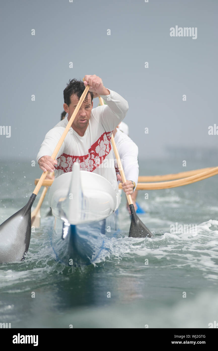 Confident male rower with team paddling outrigger canoe in race Stock ...