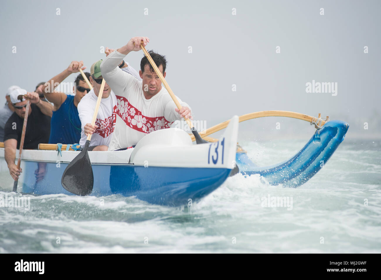 Confident male rower with team paddling outrigger canoe in race Stock ...