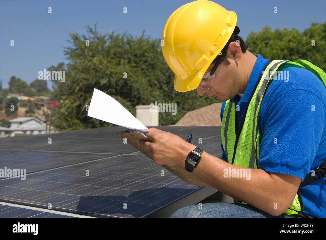 Side view of young maintenance worker making notes near solar panels on ...
