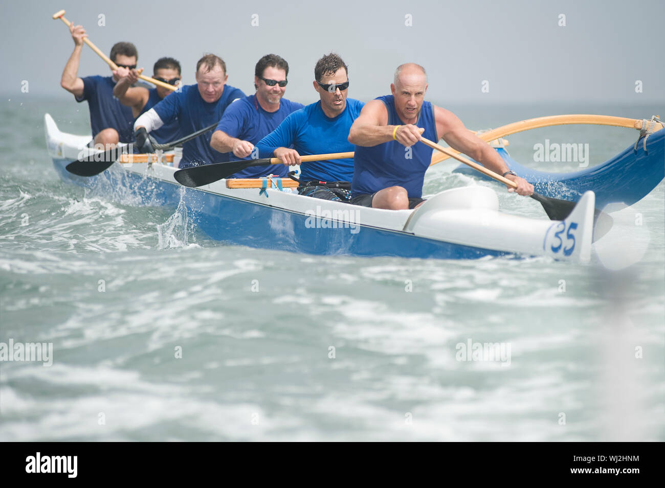 Crew of a racing outrigger canoe on water Stock Photo - Alamy
