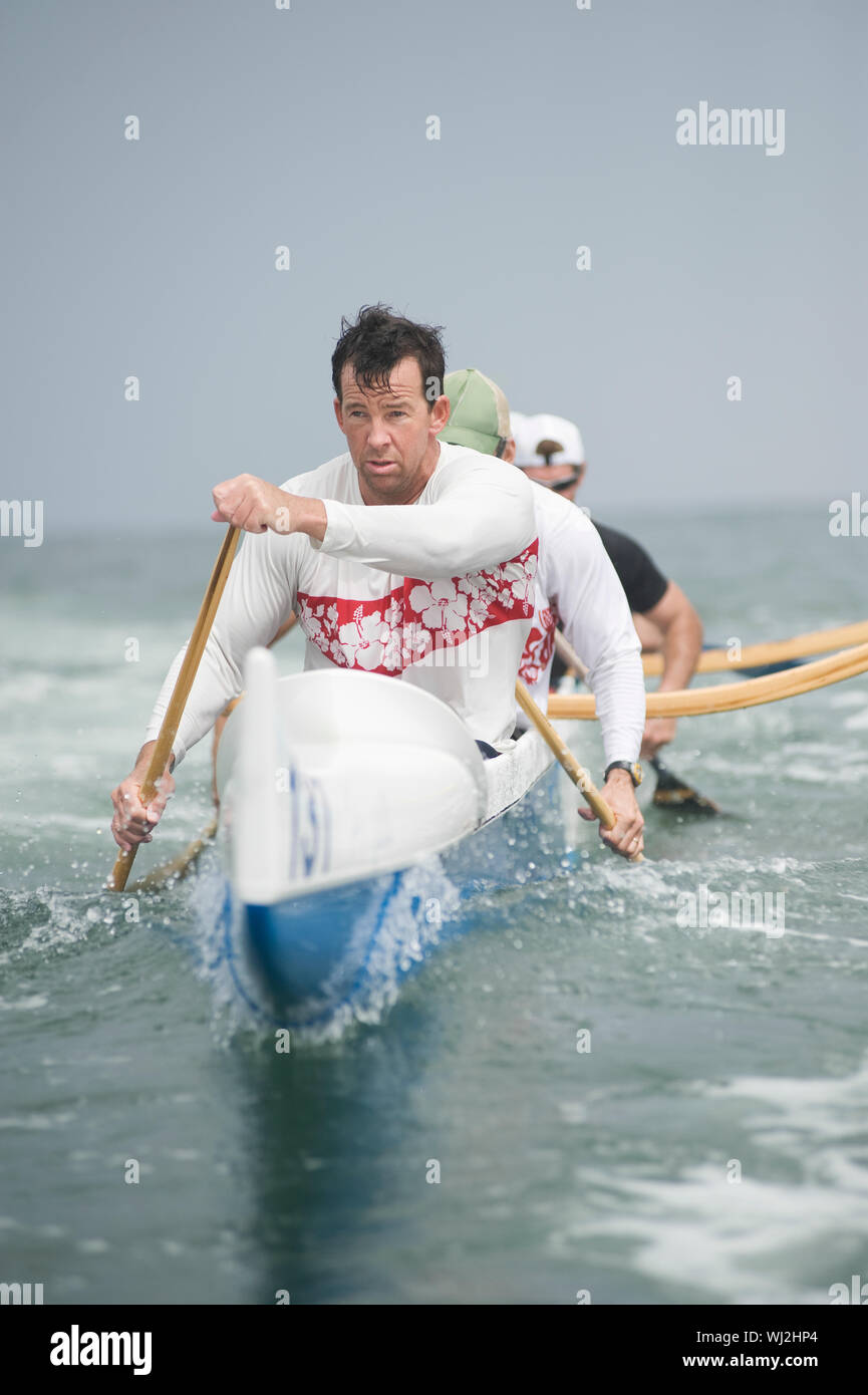 Confident male rower with team paddling outrigger canoe in race Stock ...
