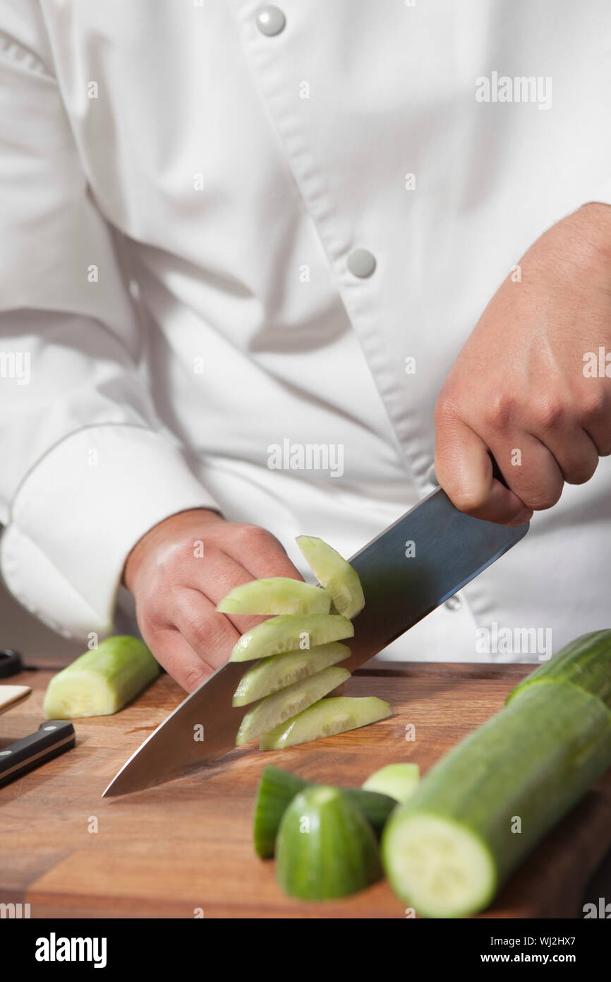 Midsection closeup of male chef slicing cake at counter in commercial ...