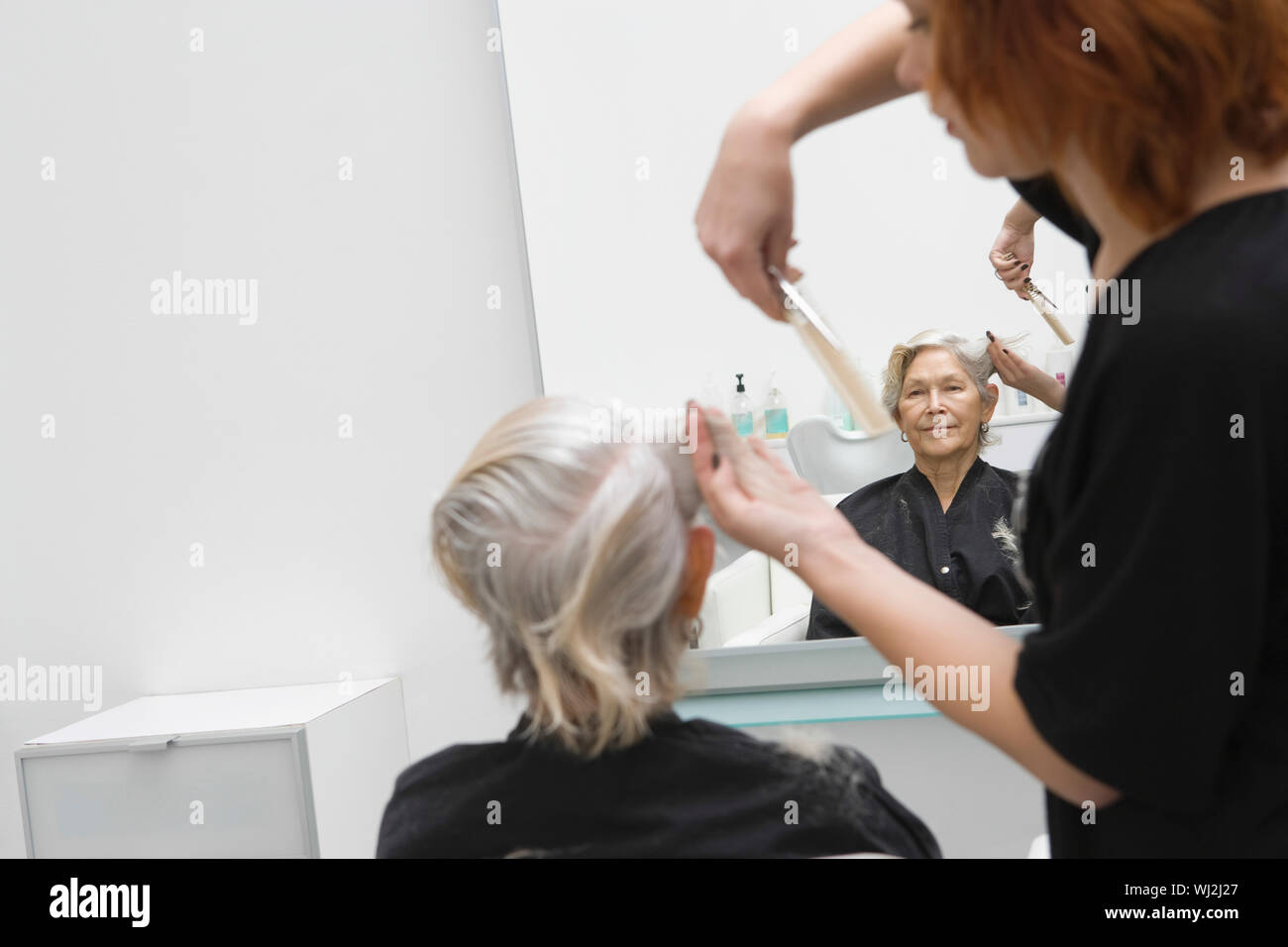 Senior woman getting haircut from female hairdresser in salon Stock ...
